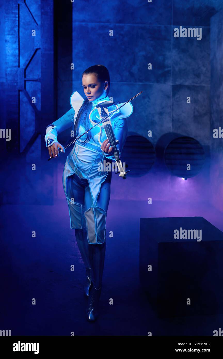 Young woman playing violin solo on stage illuminated with neon light ...