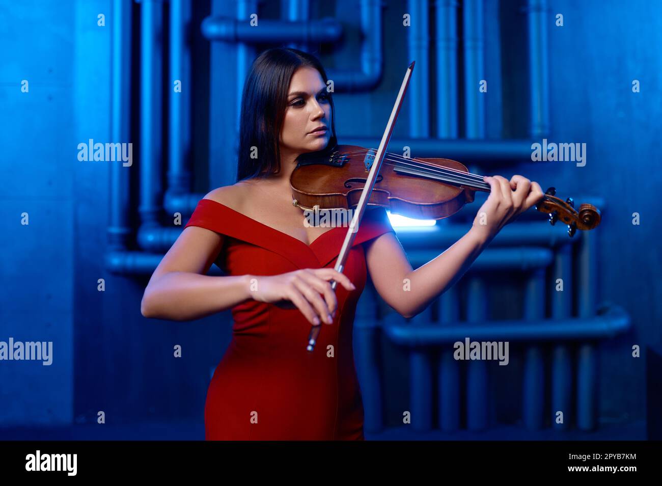 Young pretty woman playing violin solo over loft interior background ...