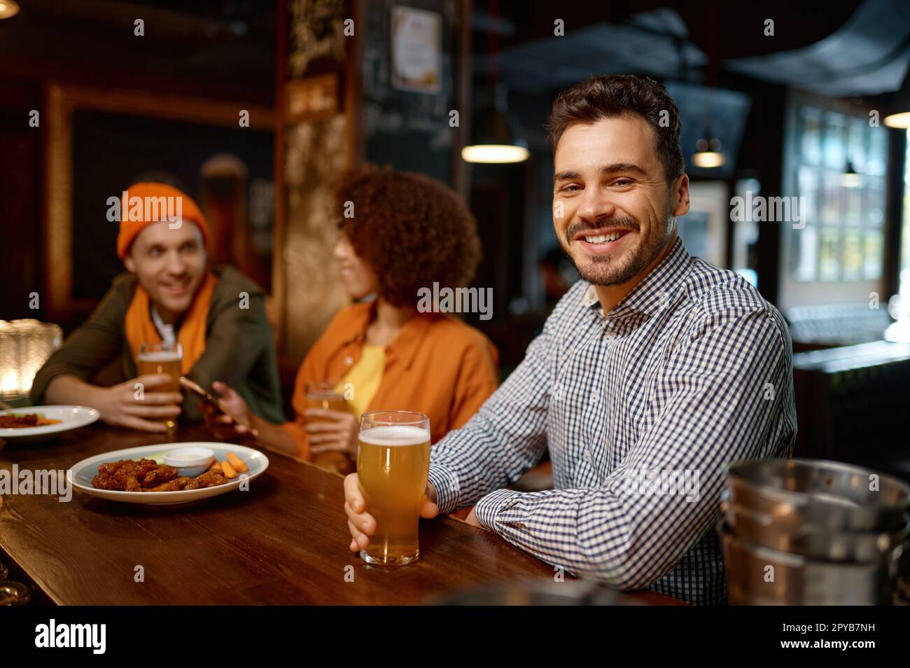 Happy smiling man sitting at sports bar counter desk looking at camera ...