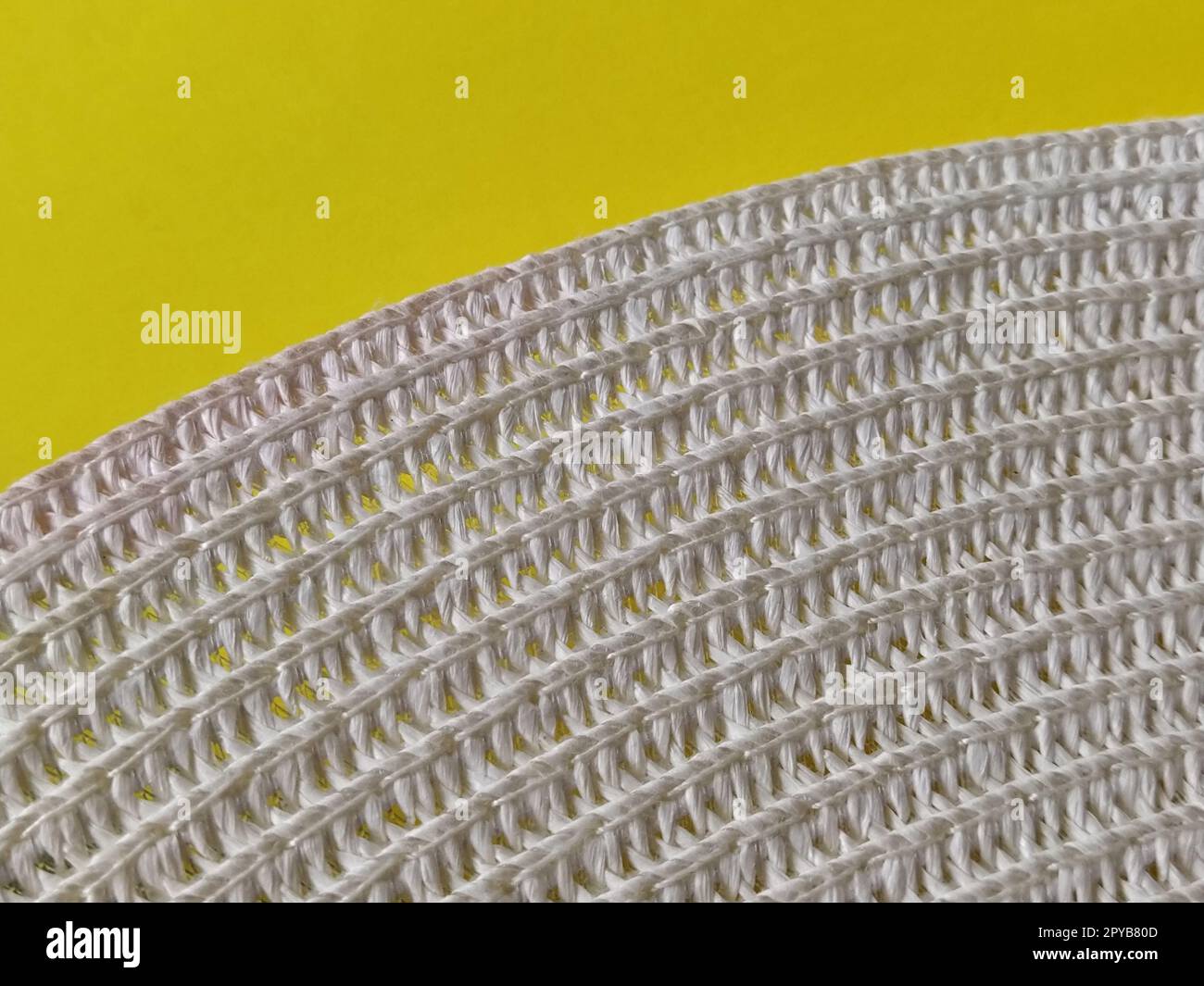 Straw hat on a yellow background. The edge of the wide brim of the hat ...