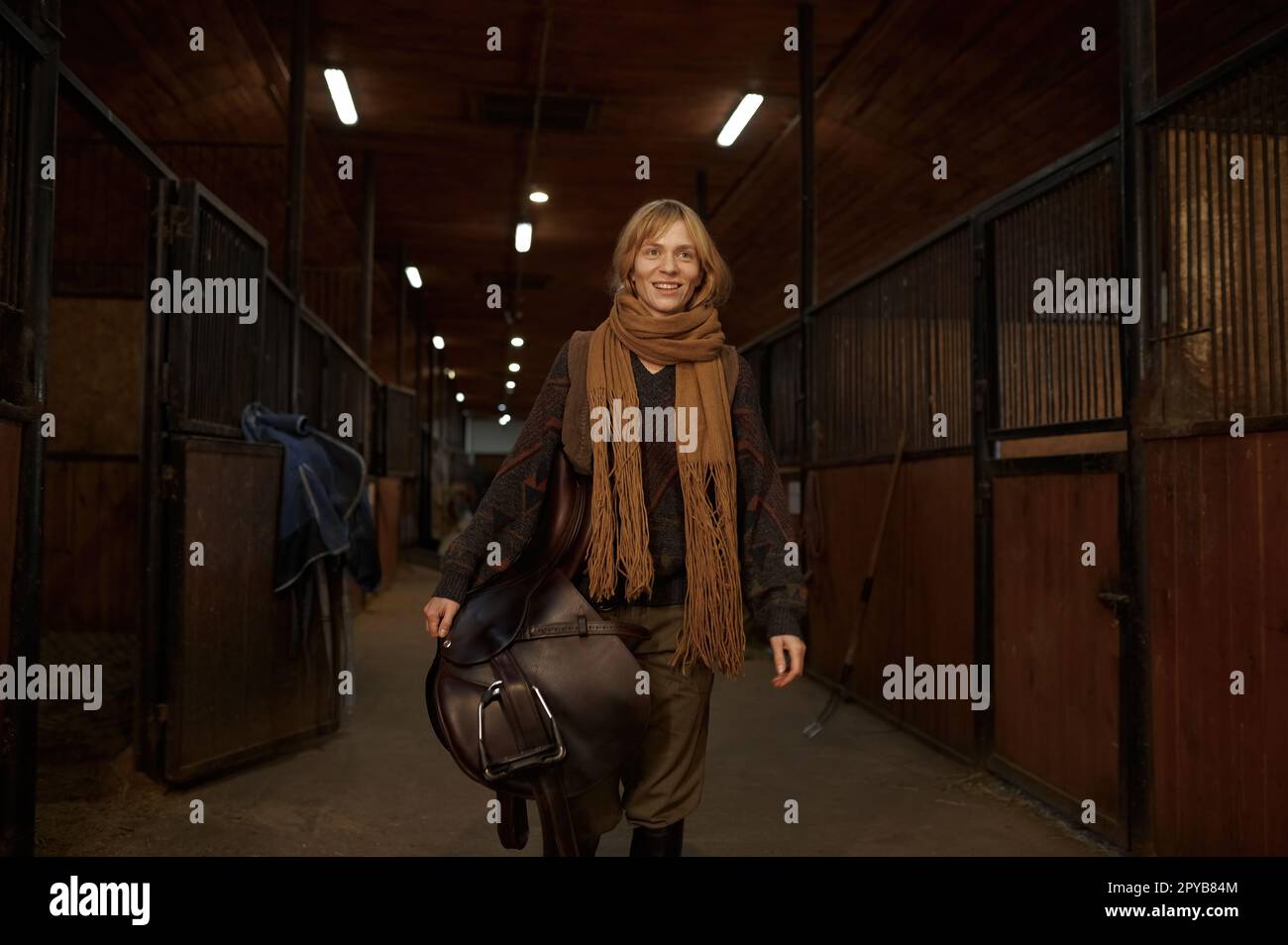 Female horse rider walking with harness in stable Stock Photo - Alamy