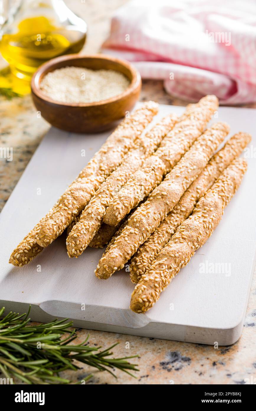 Italian grissini bread sticks with sesame seeds on white cutting board ...