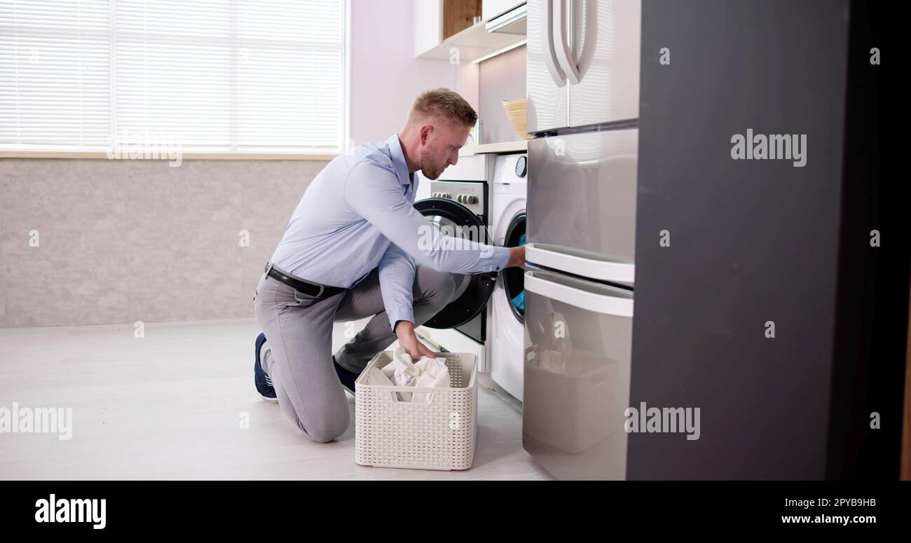 Young Man Loading Clothes Into Washing Machine Stock Photo - Alamy