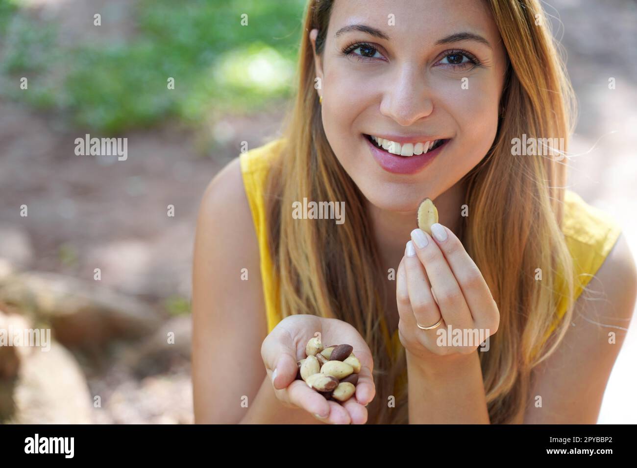 Close-up of healthy Brazilian woman picking Brazil nuts from her hand ...