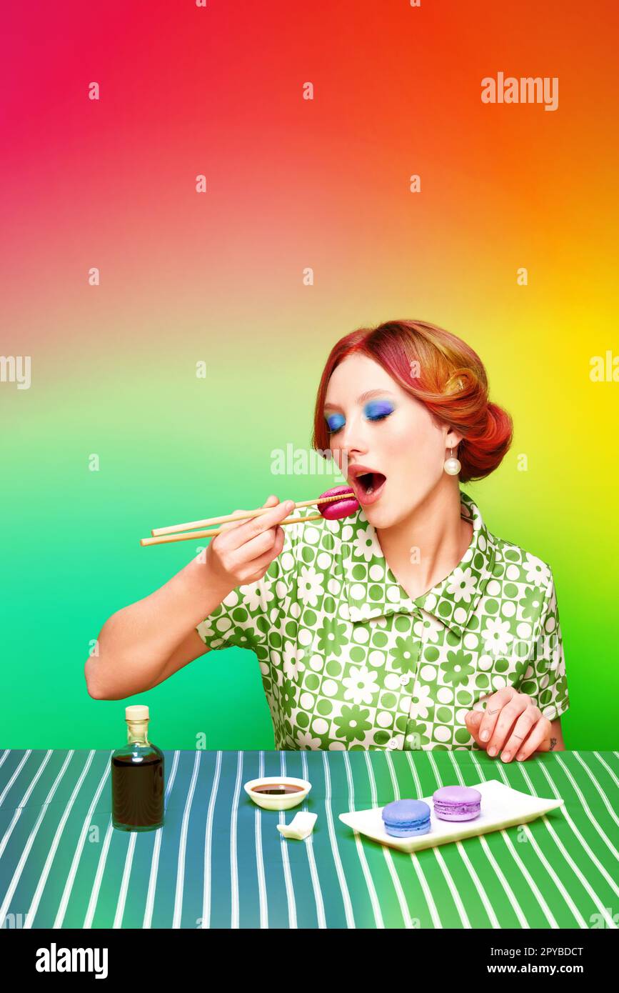 Pretty, stylish, young girl eating sweet macarons with chopsticks ...
