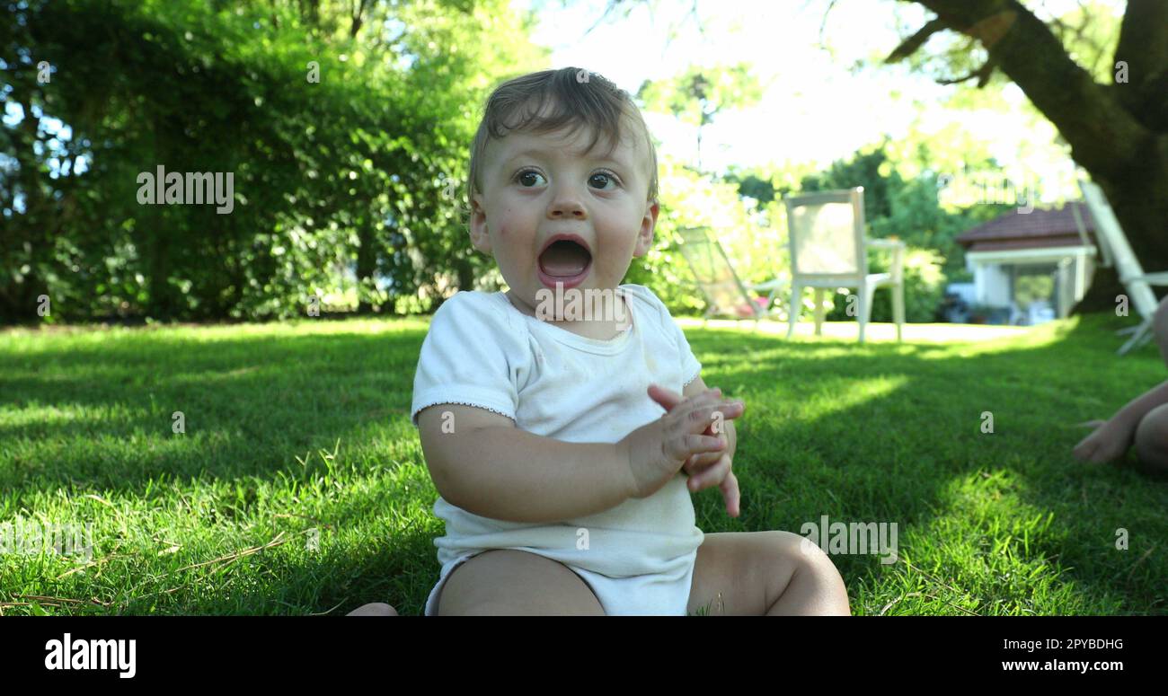 Happy baby clapping hands in outdoor garden, joyful handsome toddler ...