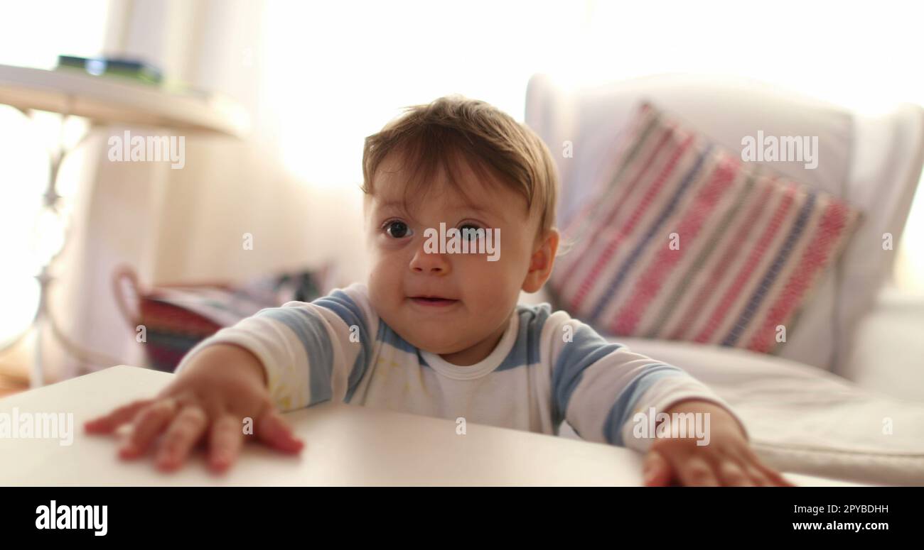 Infant toddler learning to stand by holding into table Stock Photo - Alamy