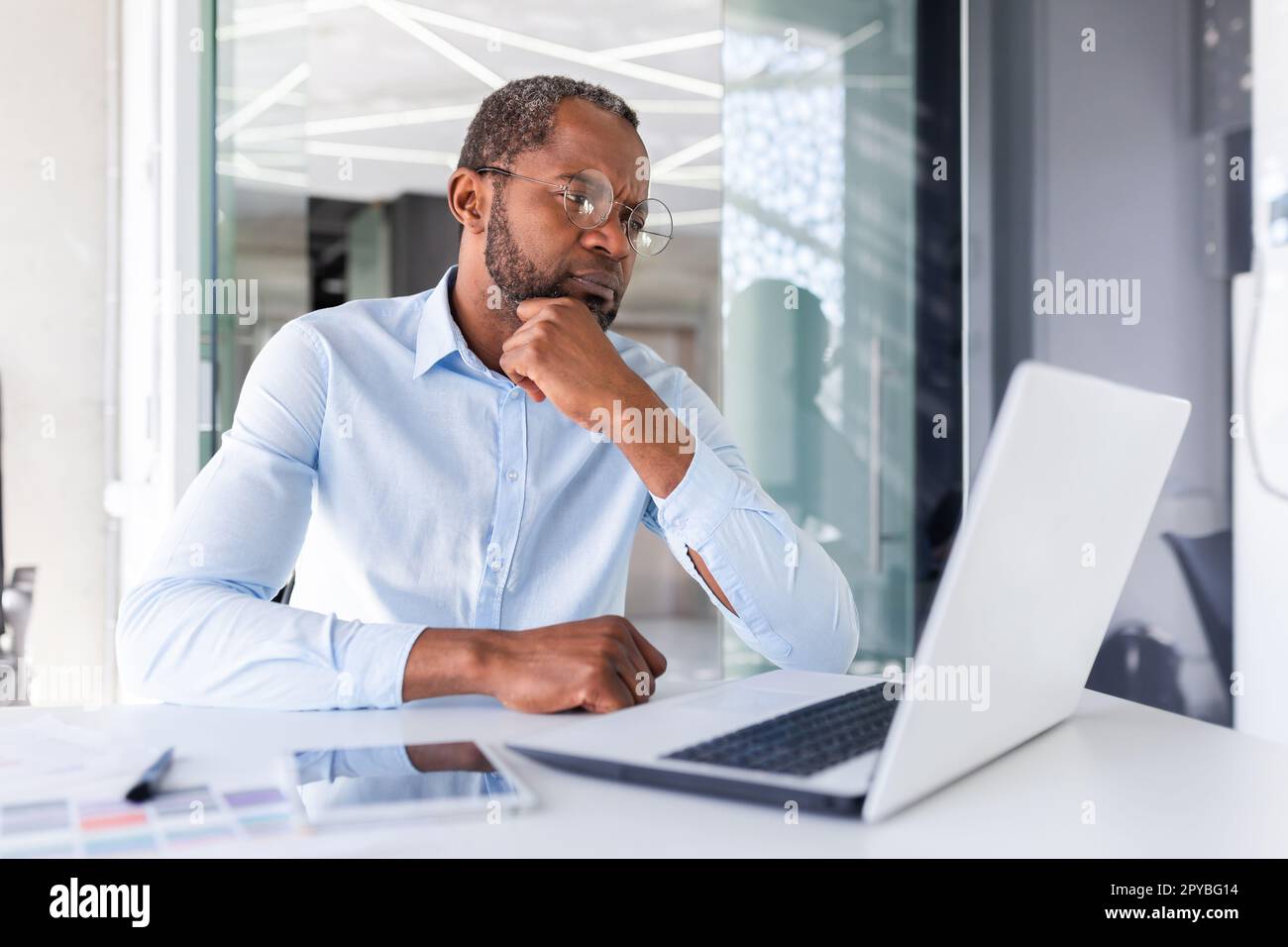 Thinking serious African American businessman working inside office ...