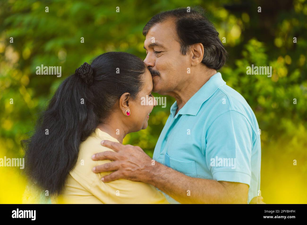 Happy senior man or husband kissing his wife's forehead by hugging at ...