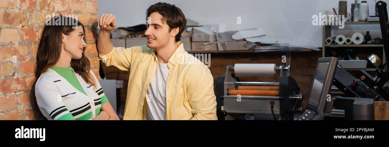cheerful man flirting with pretty colleague while standing together in ...