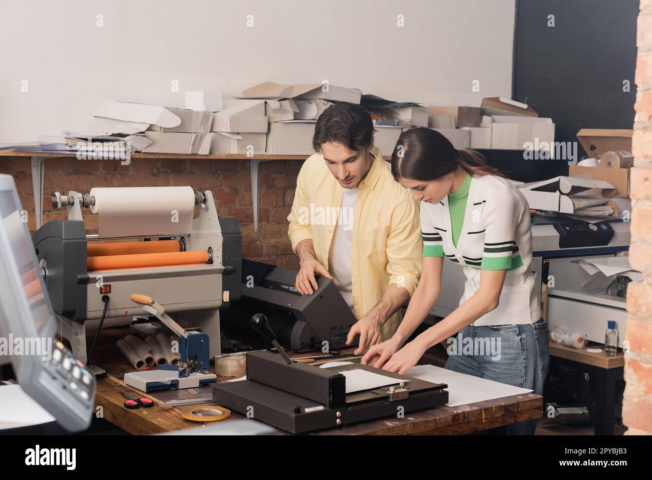 good looking publisher explaining work to colleague in print center ...