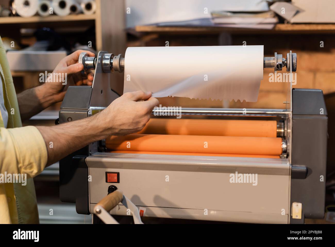 cropped view of worker pulling paper while working with print plotter ...