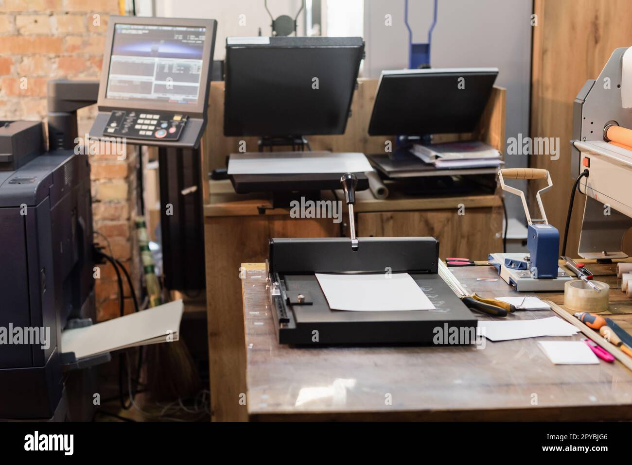 print center with modern equipment next to monitor and paper trimmer ...