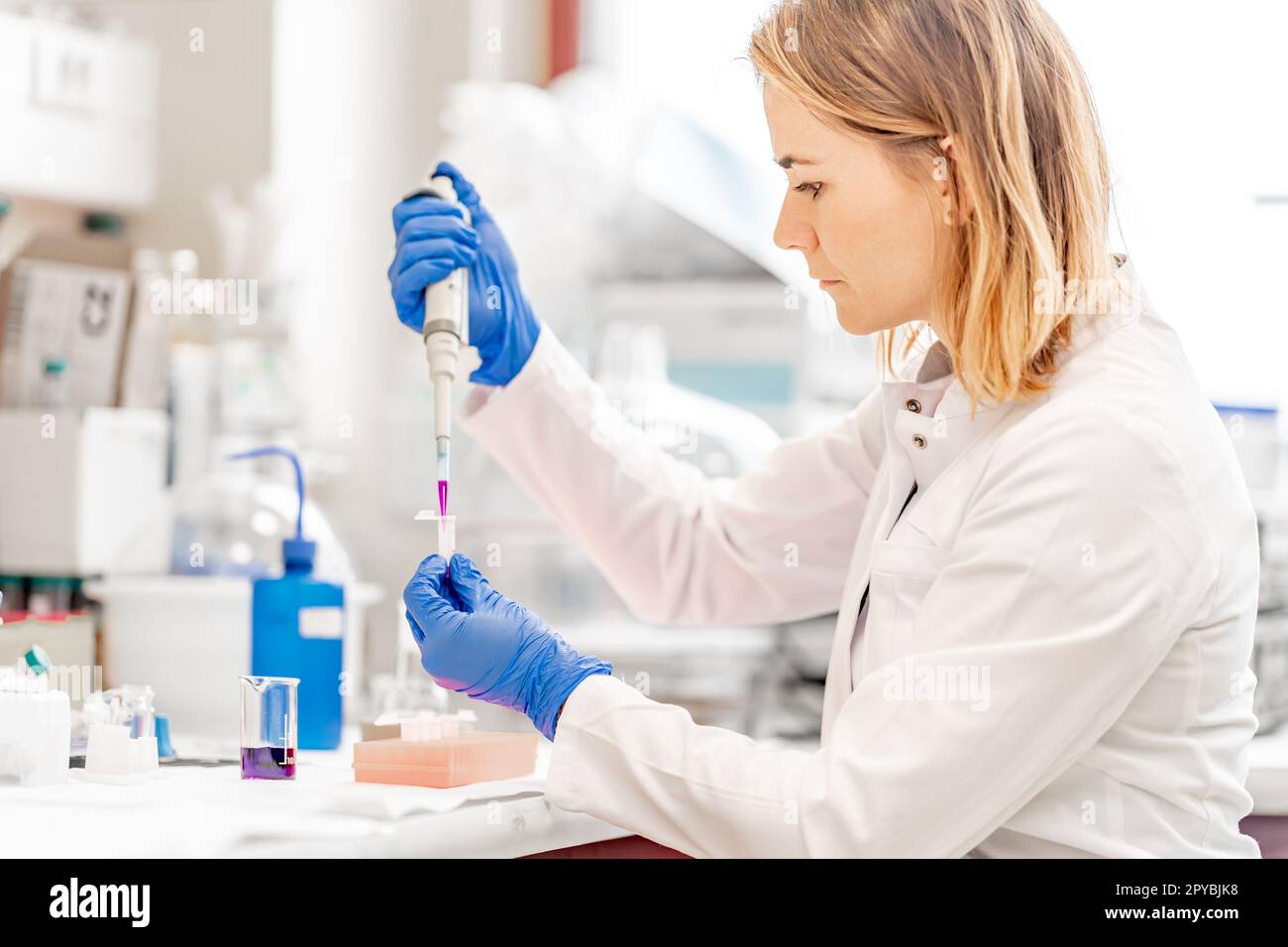 young attractive female scientist examines chemical samples of ...