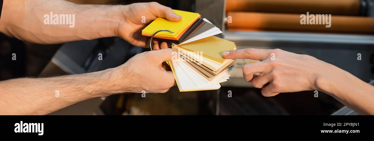 partial view of typographer pointing at color samples in print center ...