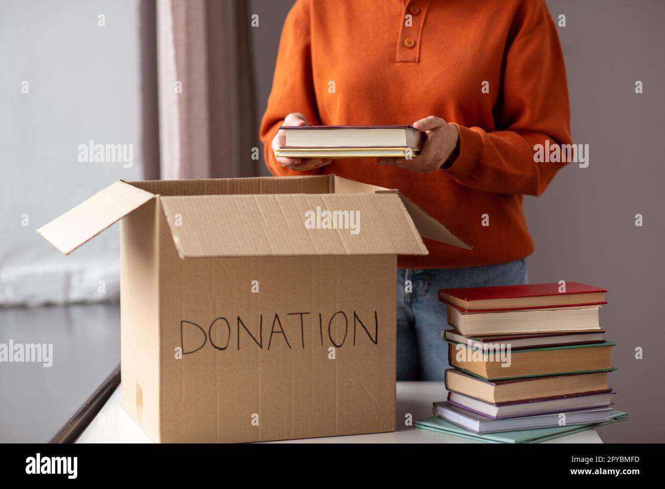 woman puts books in cardboard box for donation Stock Photo - Alamy