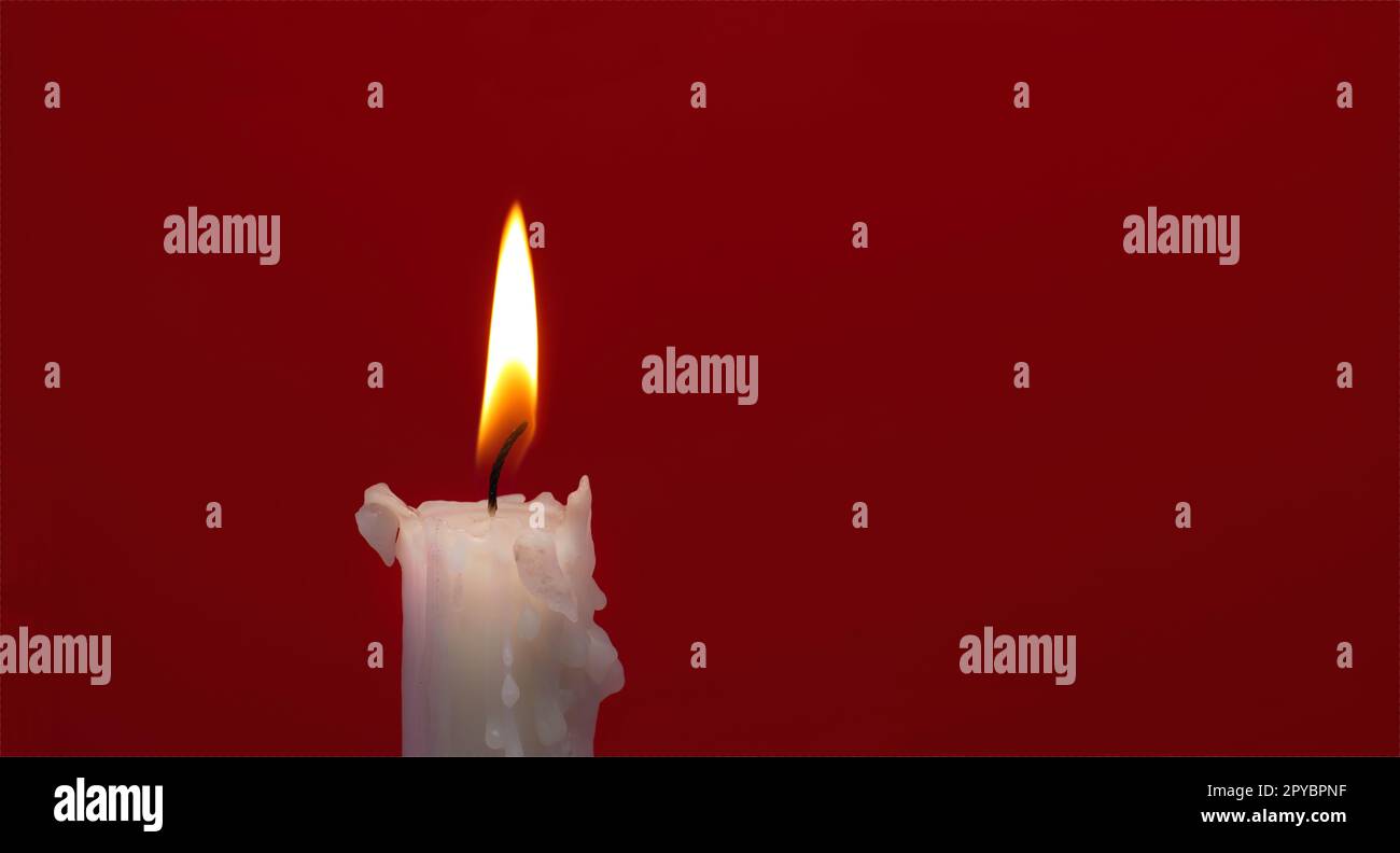 Burning wax candle against a red background Stock Photo - Alamy