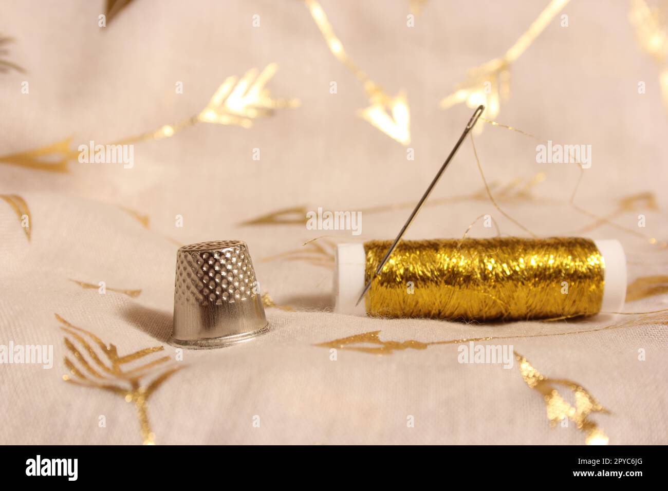 Spool of Gold Thread With Thimble on Metallic Fabric Stock Photo - Alamy