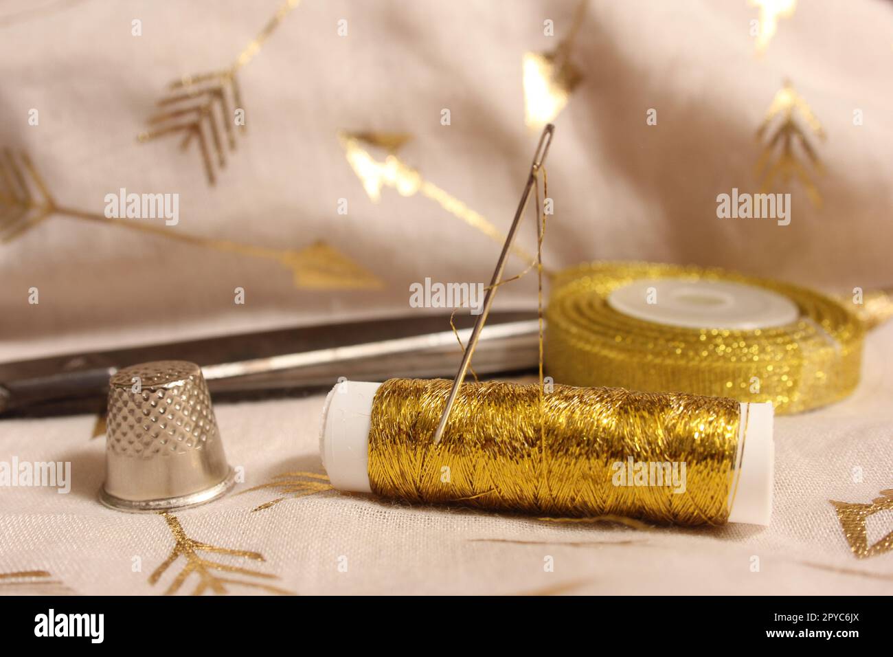 Spool of Gold Thread and Scissors With Thimble on Metallic Fabric Stock ...