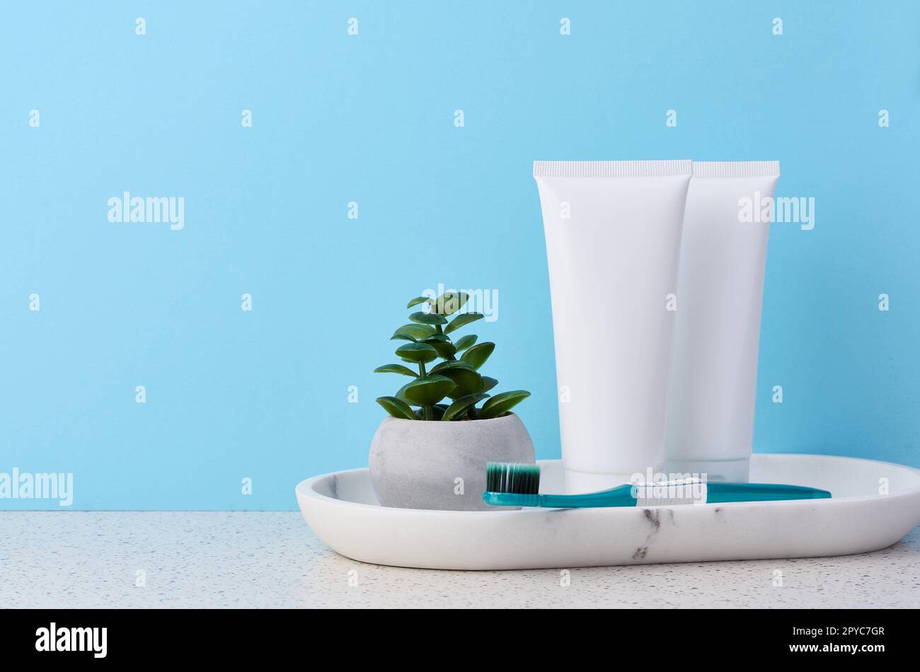 White plastic toothpaste tube and toothbrush on a bluek background ...