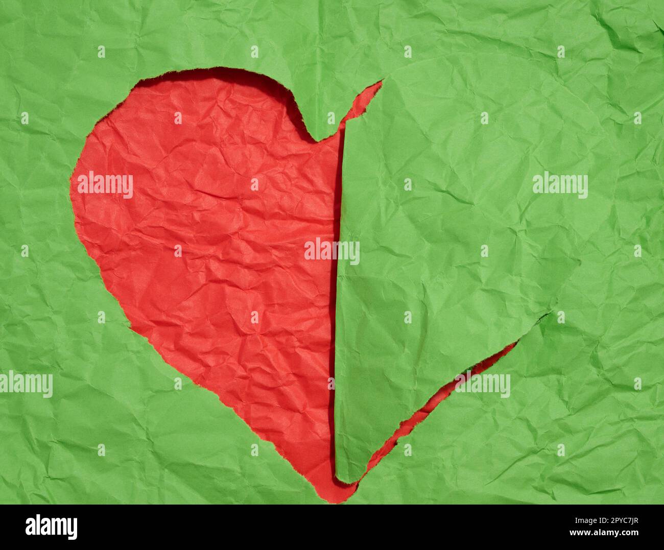 A heart cut out of green paper on a white isolated background, an ...