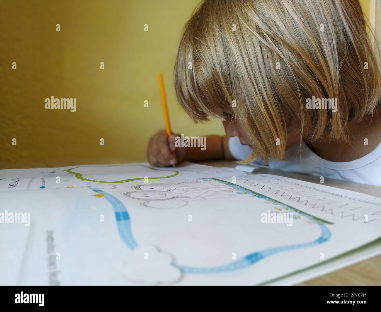 A 6-7 year old girl is reading a book or textbook and smiling. The ...