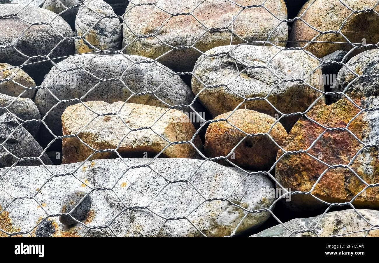 Stones rocks pinned behind a net in Mexico Stock Photo - Alamy