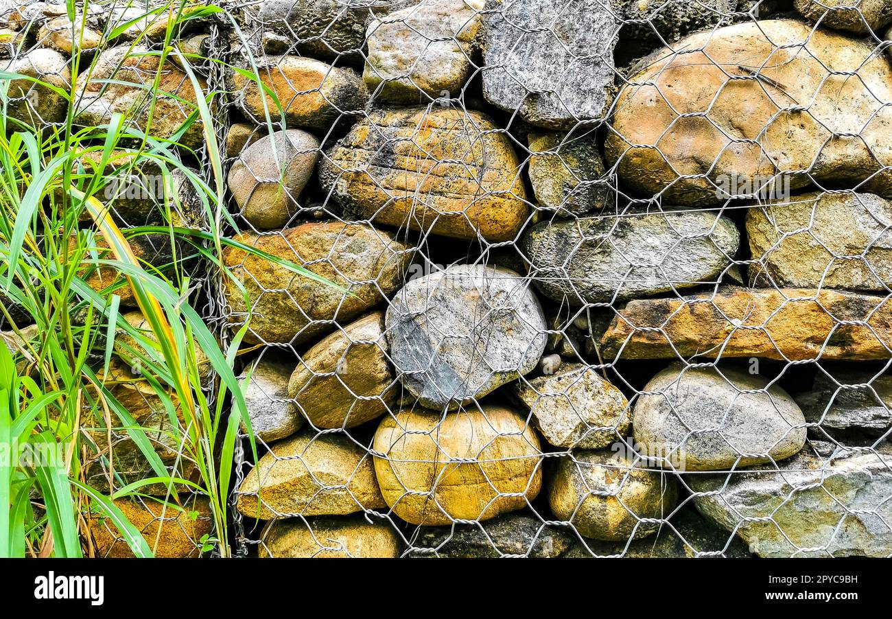 Stones rocks pinned behind a net in Mexico Stock Photo - Alamy