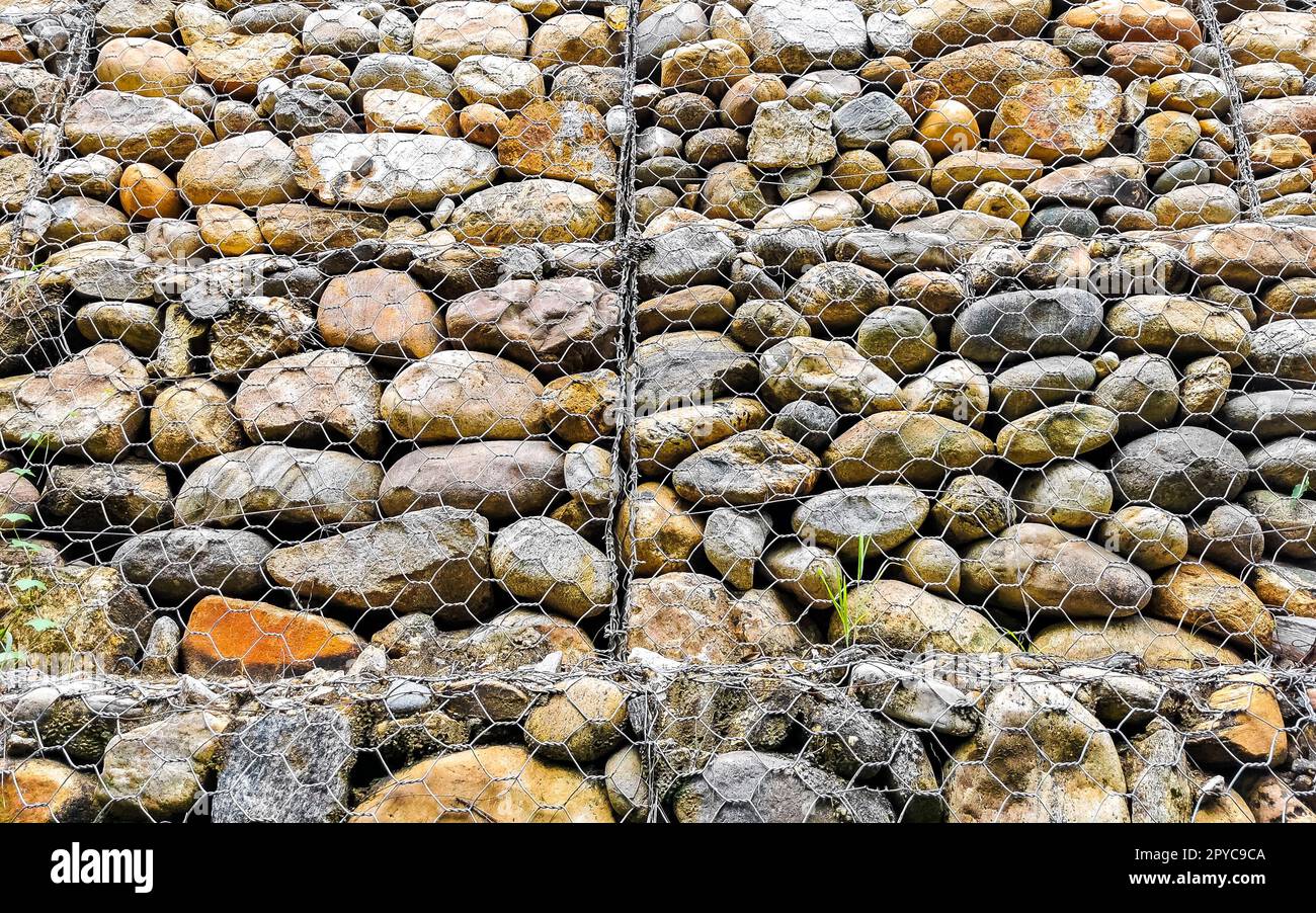 Stones rocks pinned behind a net in Mexico Stock Photo - Alamy