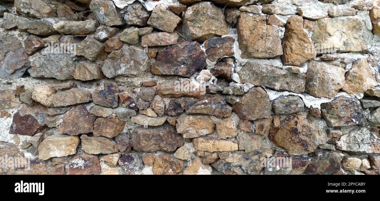 Stone wall. Stacked large cobblestones in warm colors. Tower in Kula ...