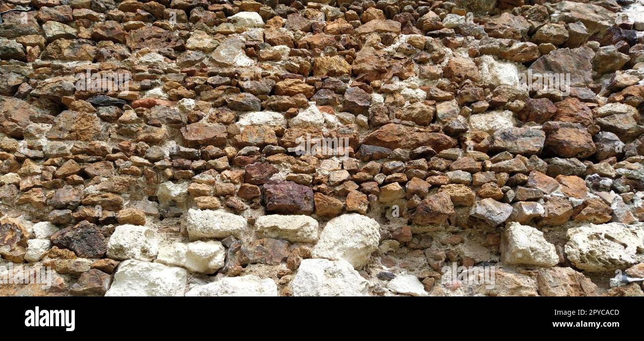 Stone wall. Stacked large bricks and cobblestones in warm colors. Loose ...