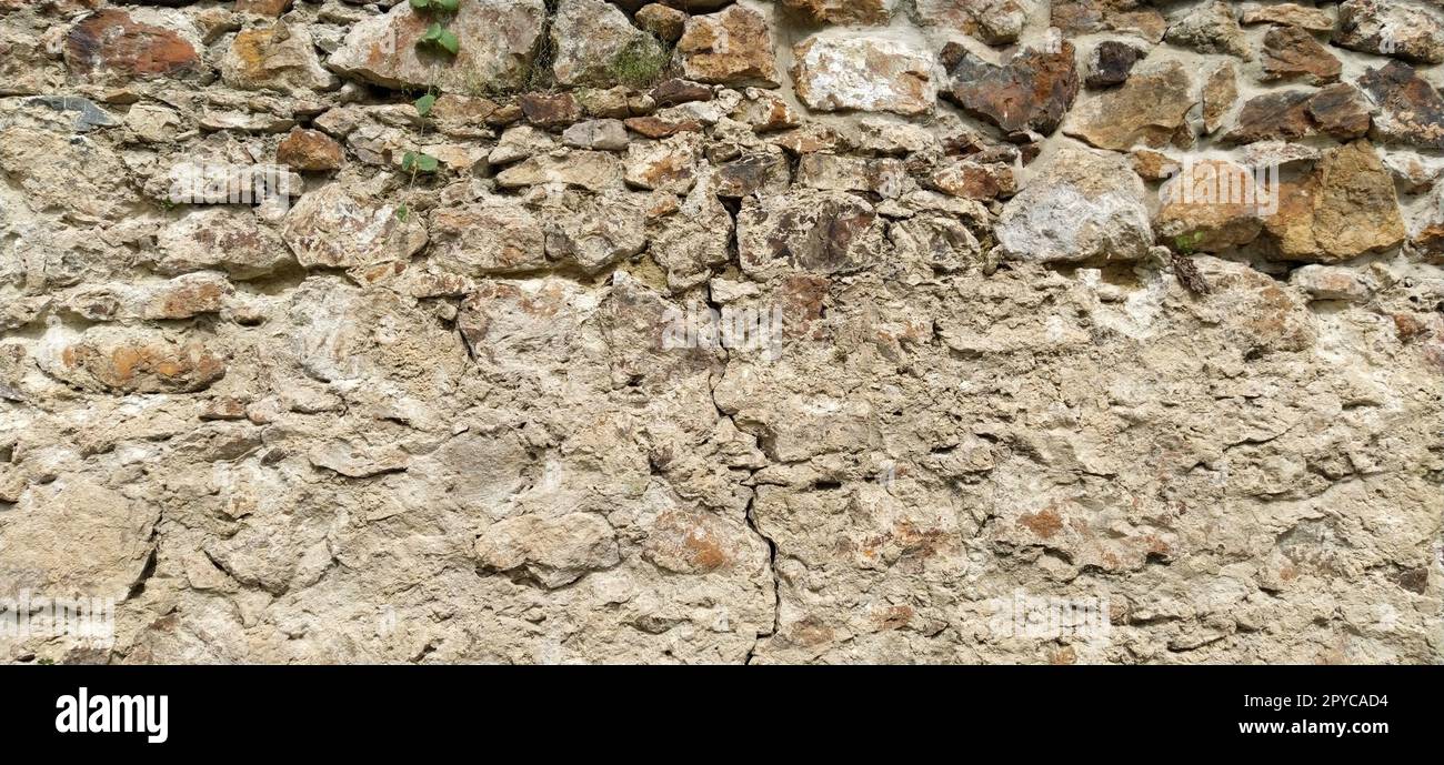 Stone wall. Stacked large cobblestones in warm colors. A crack in the ...