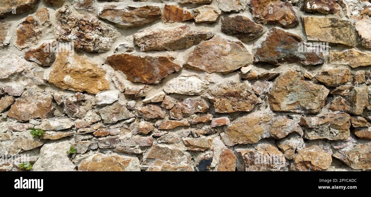 Stone wall. Stacked large cobblestones in warm colors. Tower in Kula ...