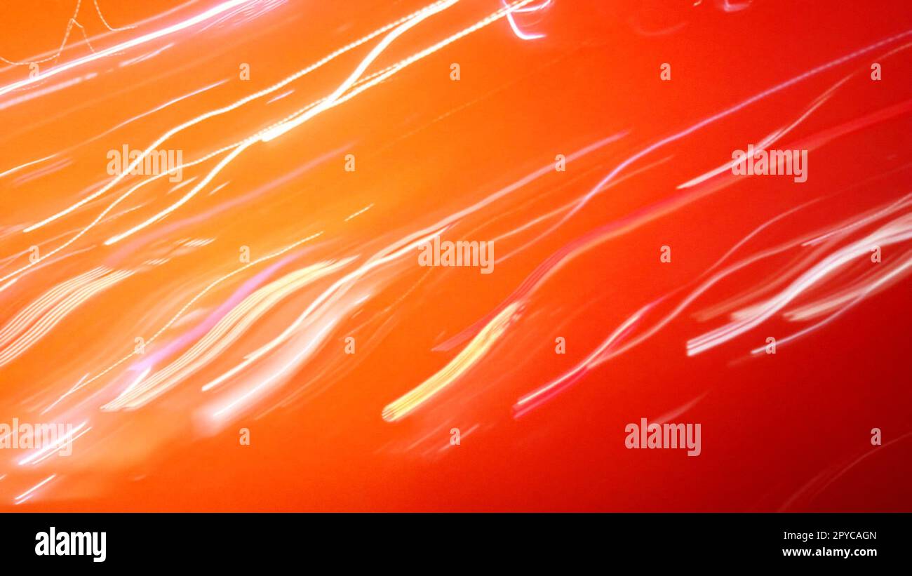 Bright red-orange background with traces of headlights, lights or rays ...