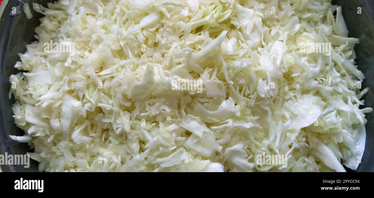 Shredded white cabbage in a saucepan. Close-up of green vegetable salad ...