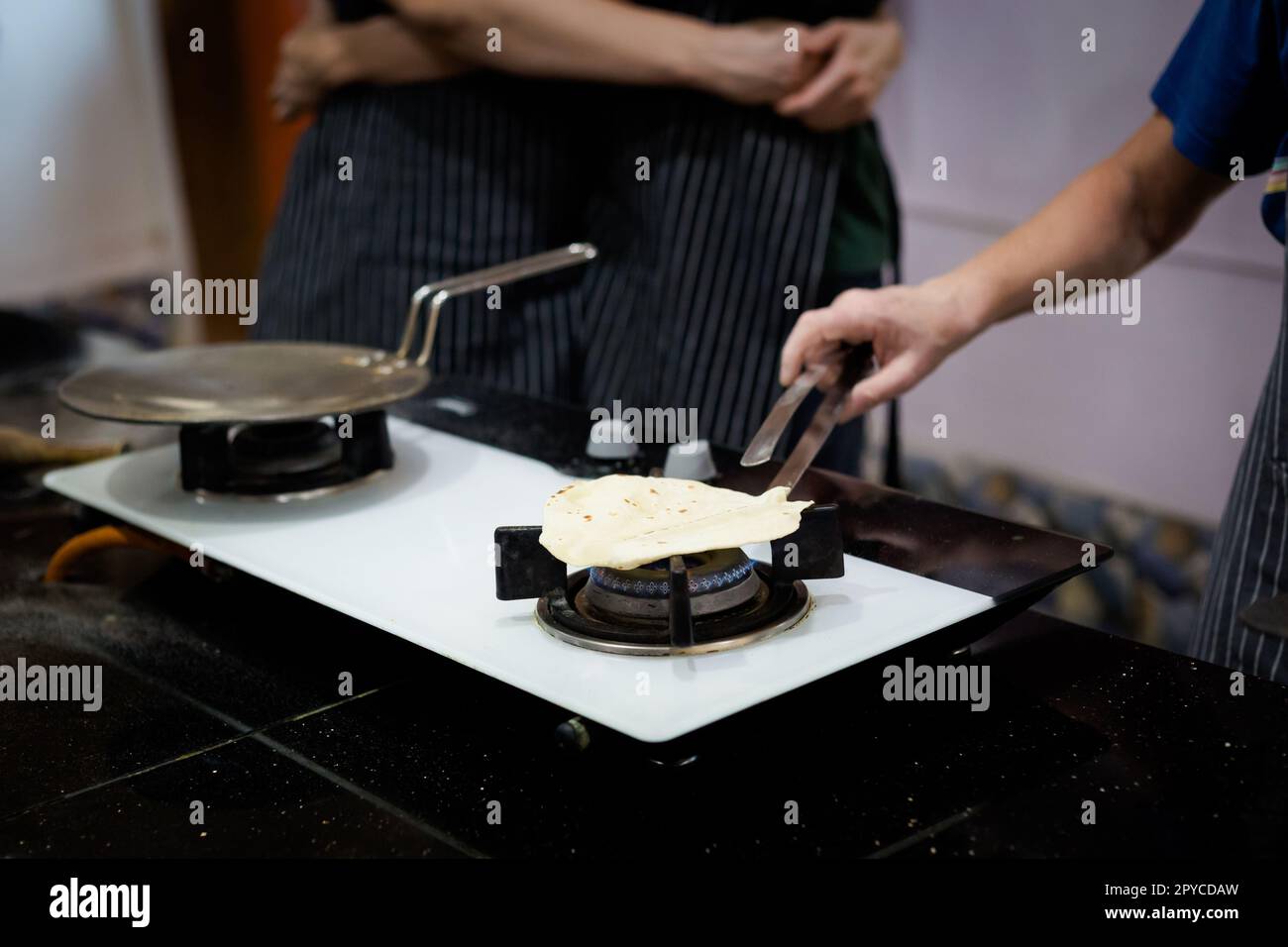 Traditional way of preparing indian food, making roti bread. Picture of ...