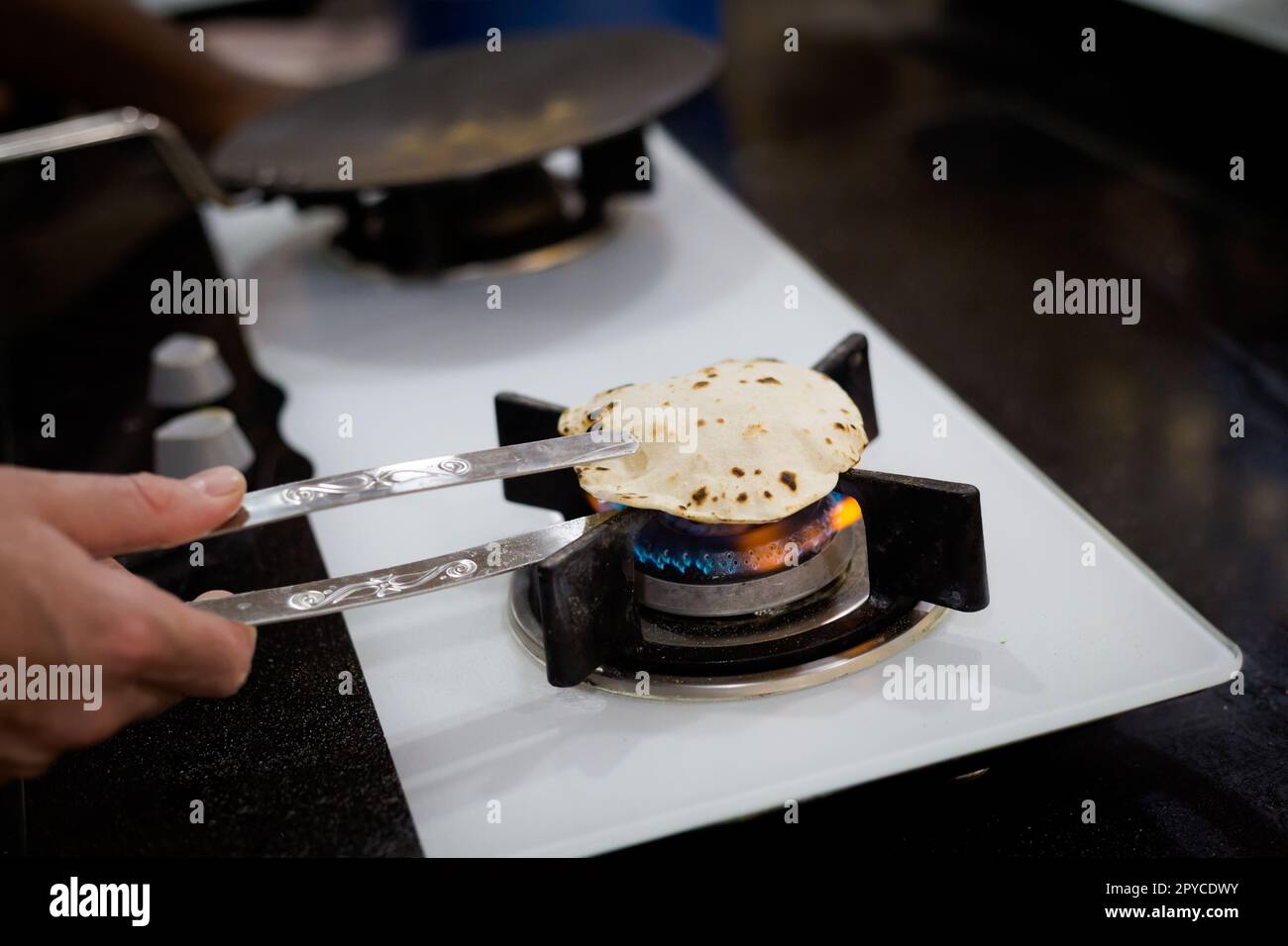 Traditional way of preparing indian food, making roti bread. Picture of ...