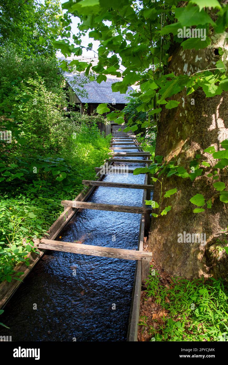 Vertical image of a sluice with flowing water in green nature setting ...