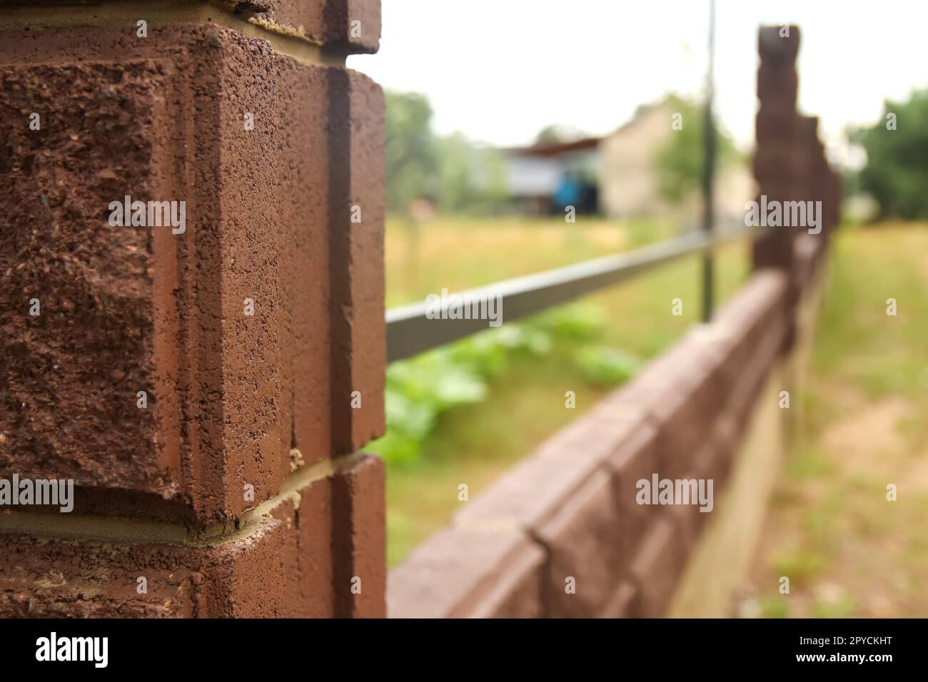 Brown metal profile fence with block posts. Incline construction ...