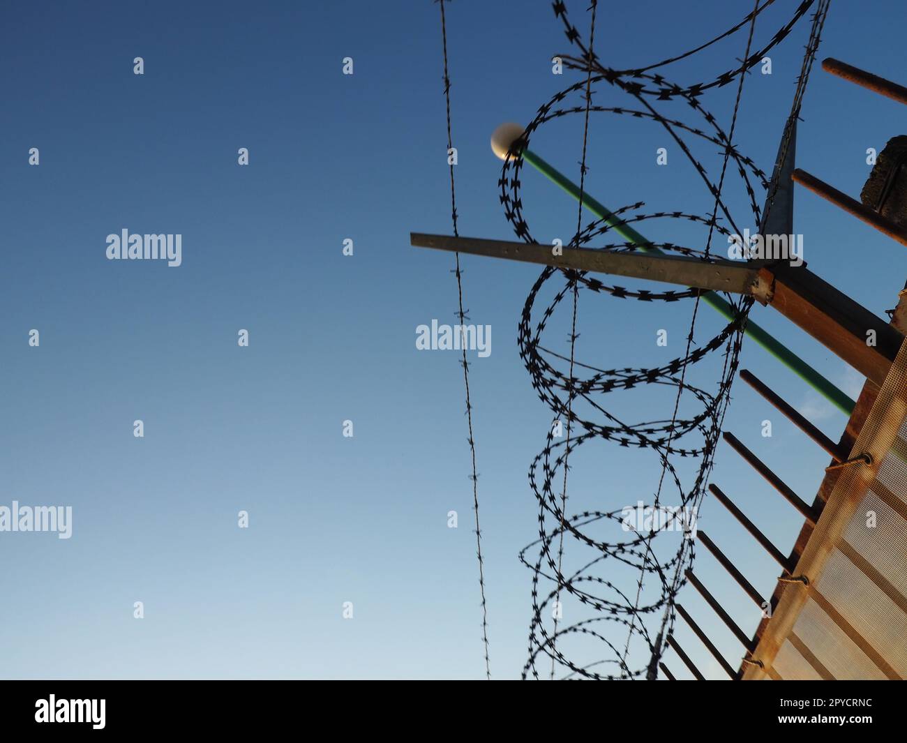 Barbed wire in skeins and stretched against the blue sky. Barbed wire ...