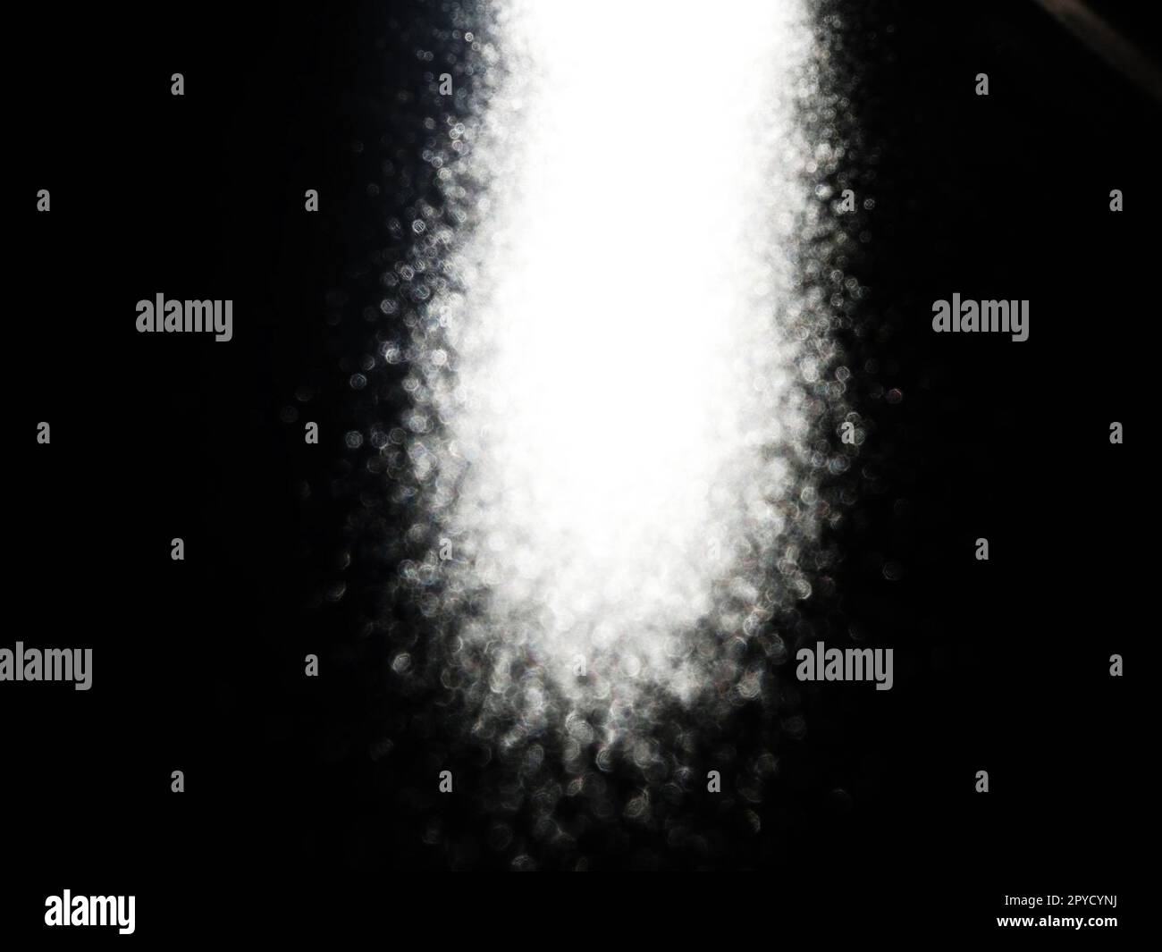 White bokeh and beam on a black background. Blurred glow from above on ...