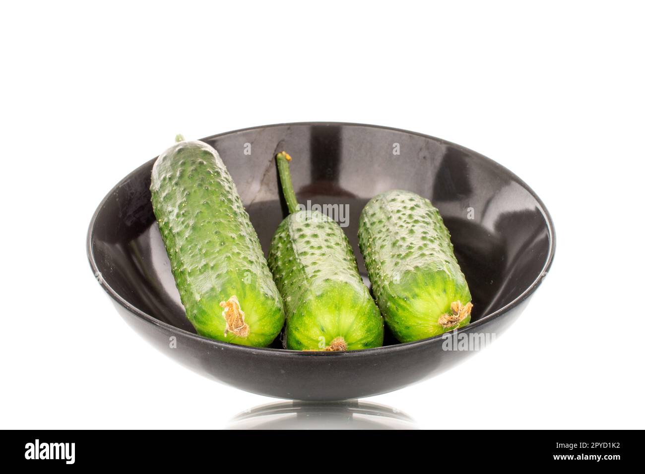 Three ripe green cucumbers on a black ceramic plate, macro, isolated on ...