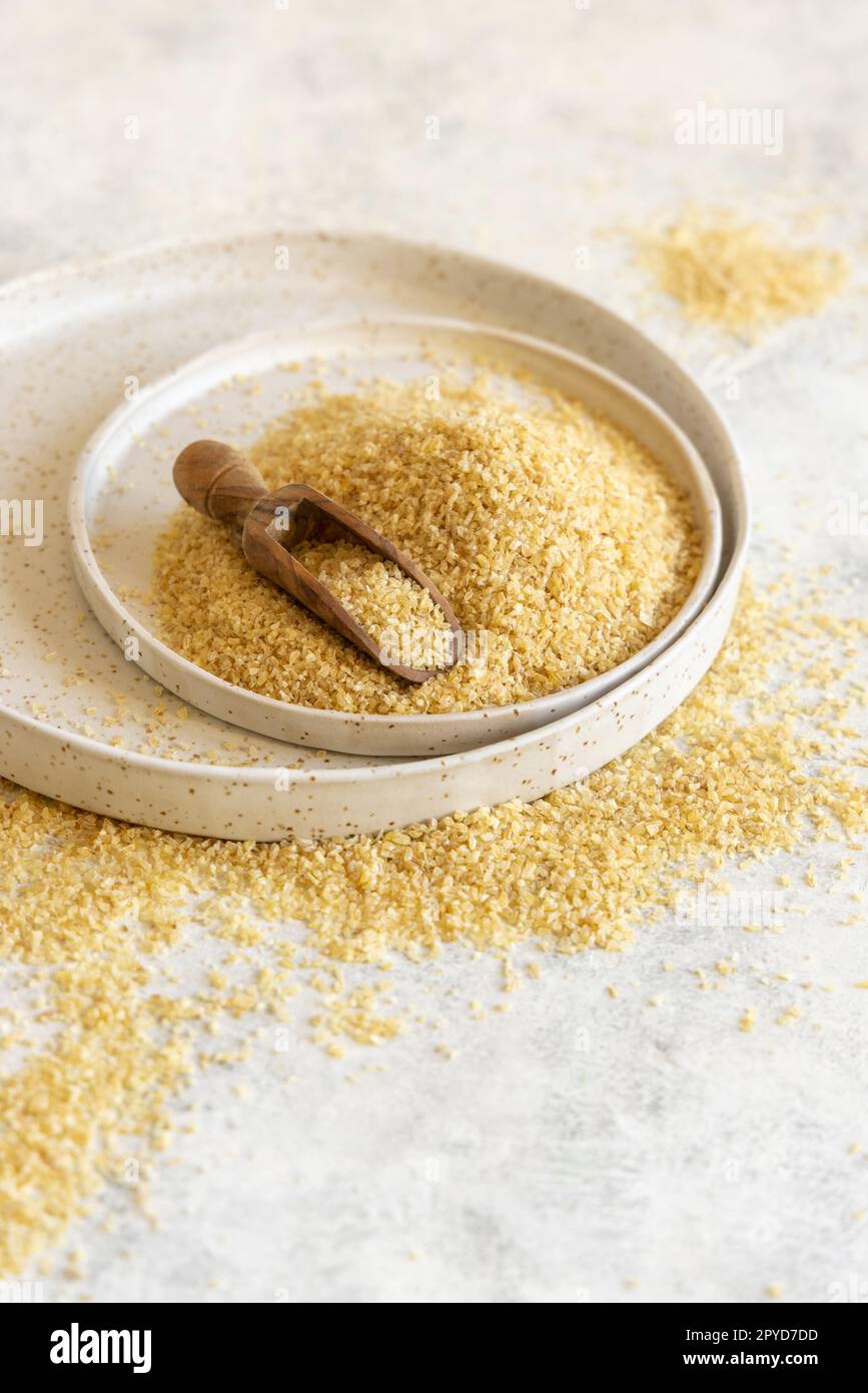 Pile of Dry uncooked bulgur wheat grain with a scoop on a plate close ...