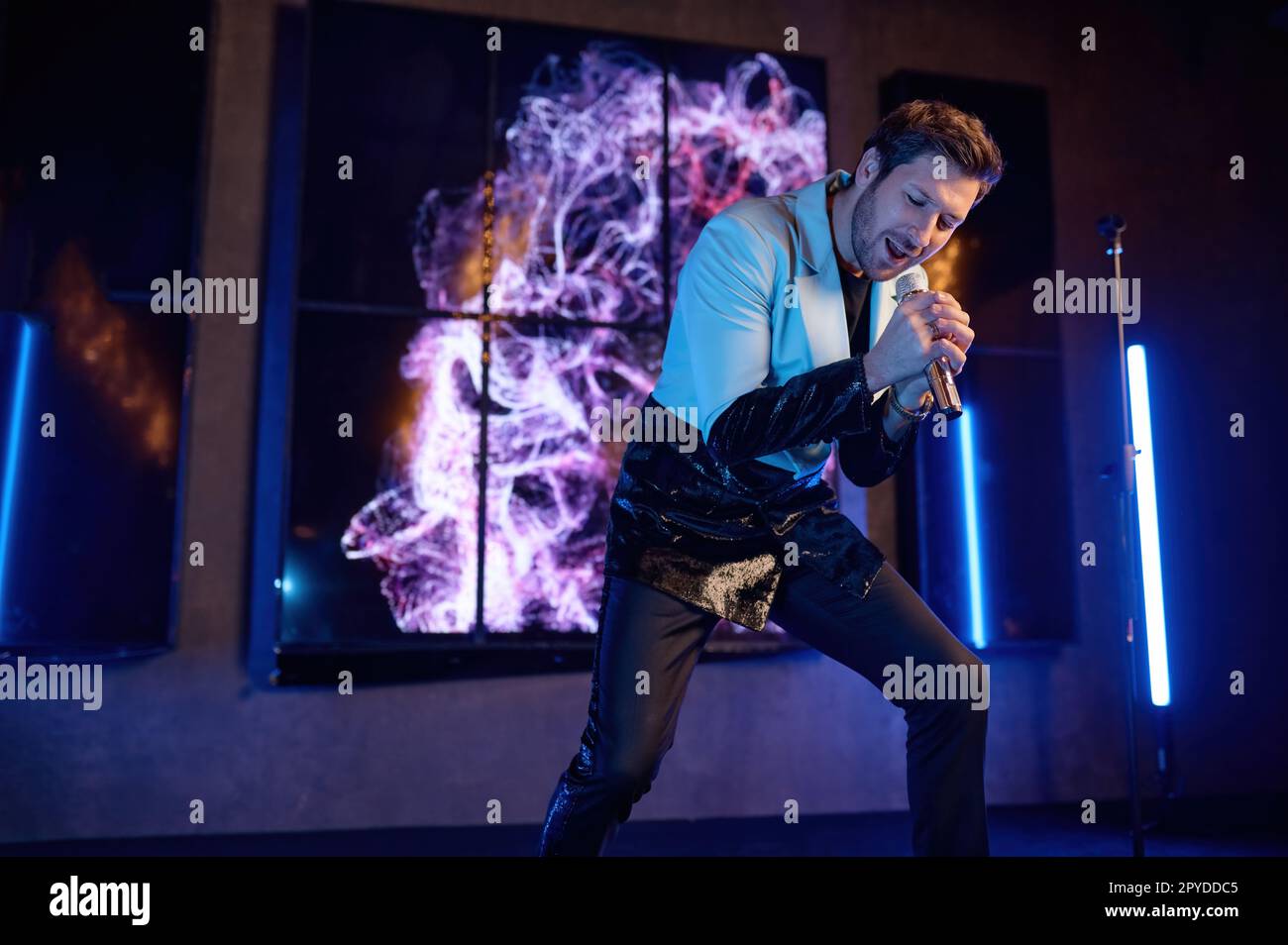 Man with enthusiastic face holding microphone and singing song on stage ...