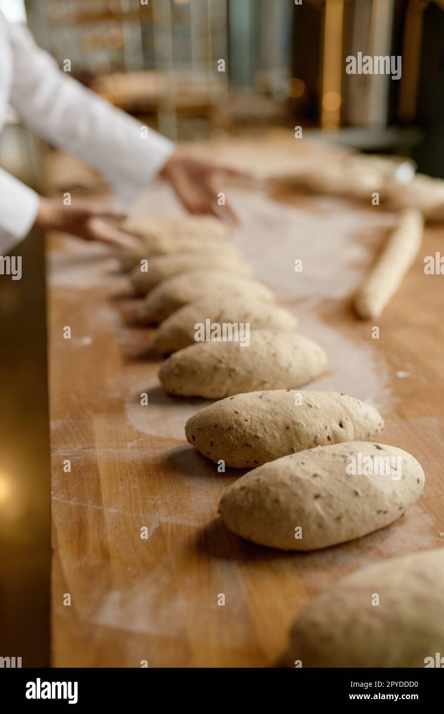 Baker working in bakery, forming baguettes from raw dough Stock Photo ...
