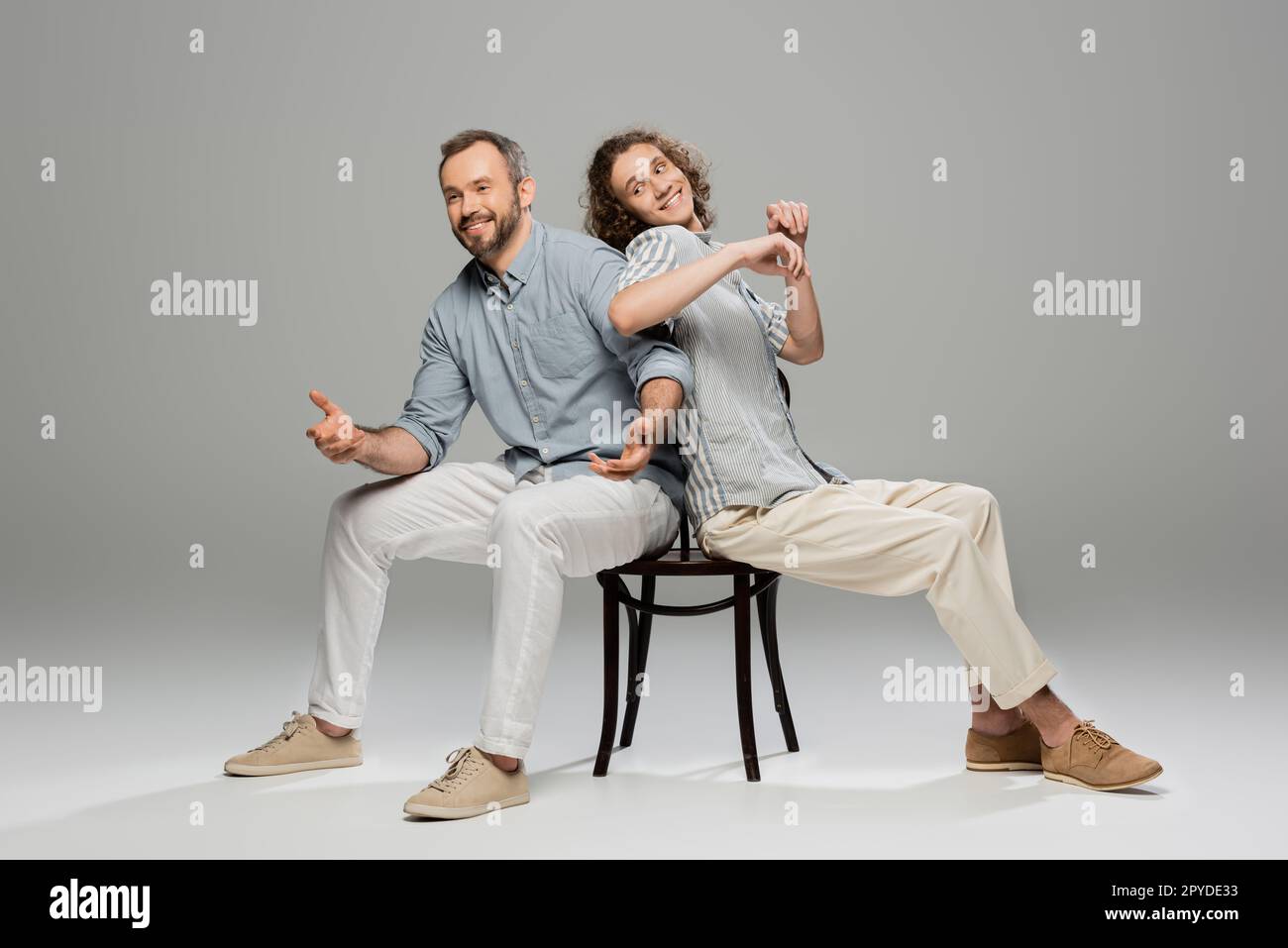 happy father and carefree teenage son having fun and pushing each other ...