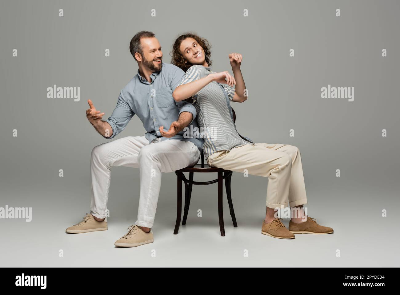 smiling father and teenage son having fun and pushing each other while ...