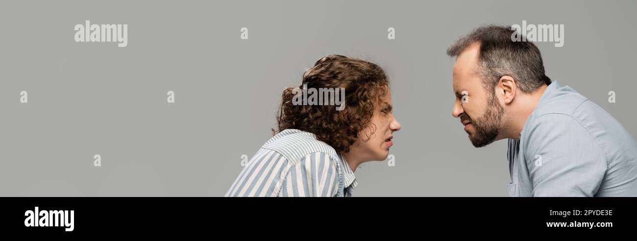 side view of angry father and teenage son looking at each other ...
