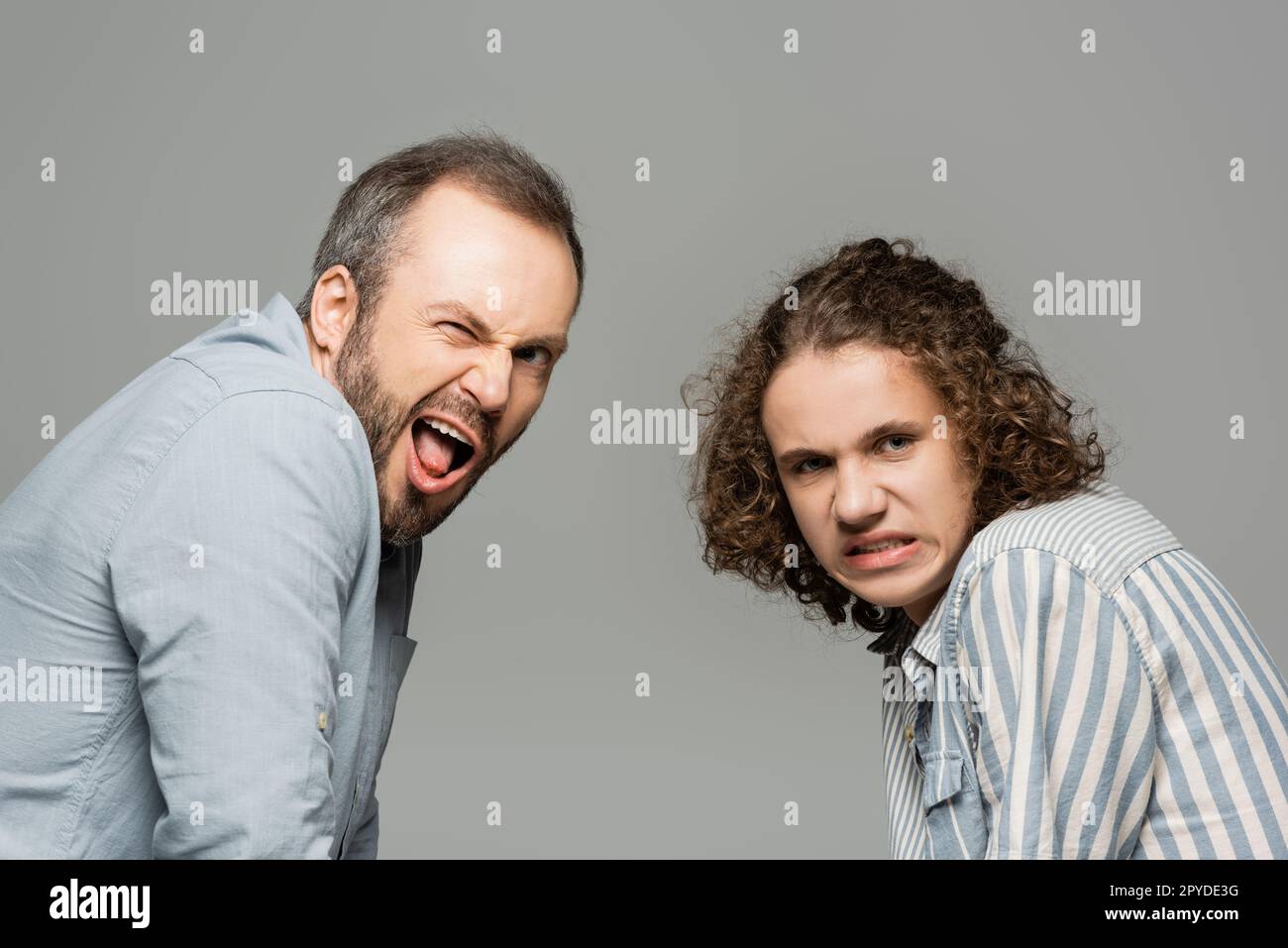father with opened mouth and disgusted teenage son grimacing and ...