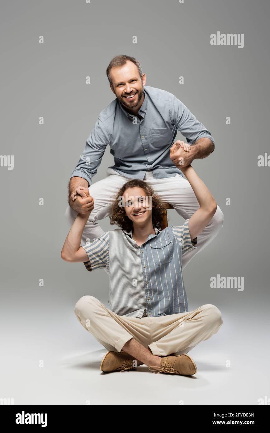 bearded father sitting on chair and holding hands with positive ...